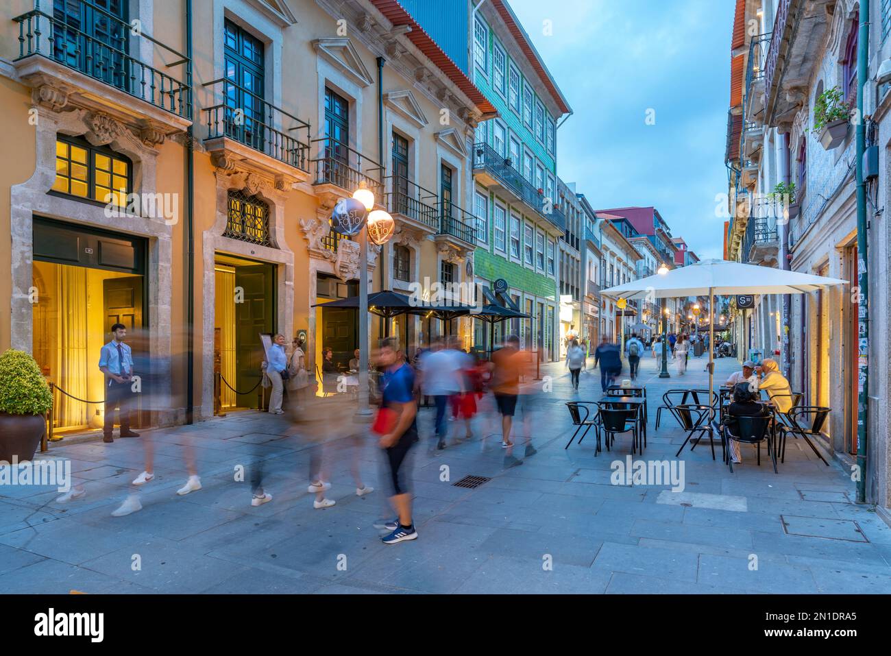 View of busy street with cafes and bars in old town Porto at dusk ...