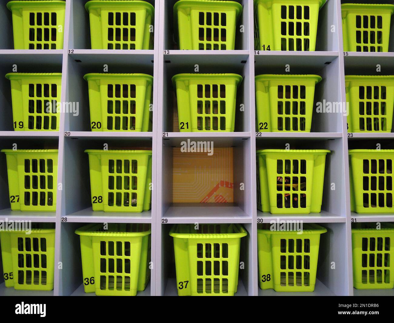 Empty cell among filled cells with plastic storage boxes at storage ...