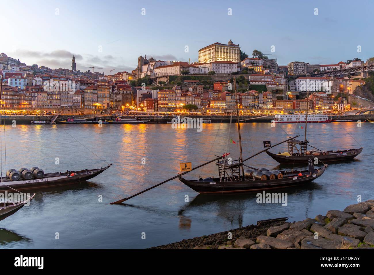 View of Douro River and Rabelo boats aligned with colourful buildings ...