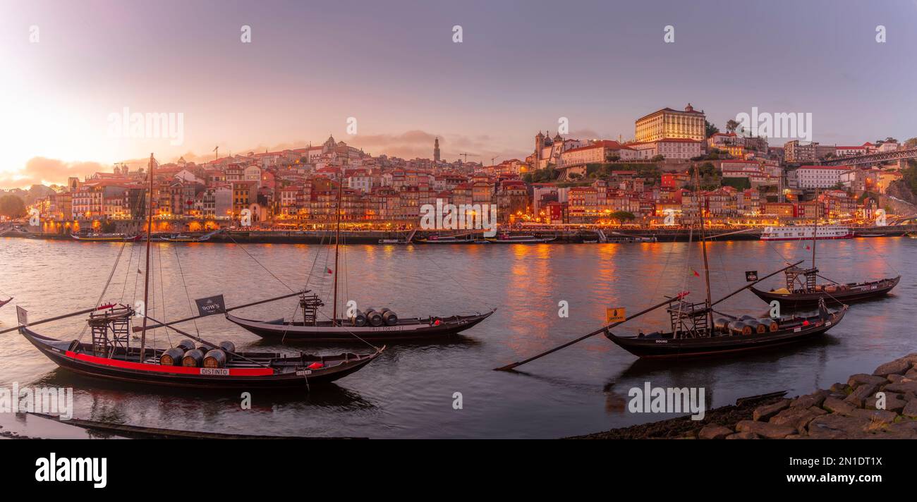 View of Douro River and Rabelo boats aligned with colourful buildings ...