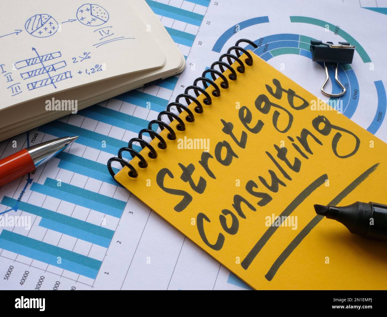 Papers with charts and notebook with inscription Strategy consulting ...