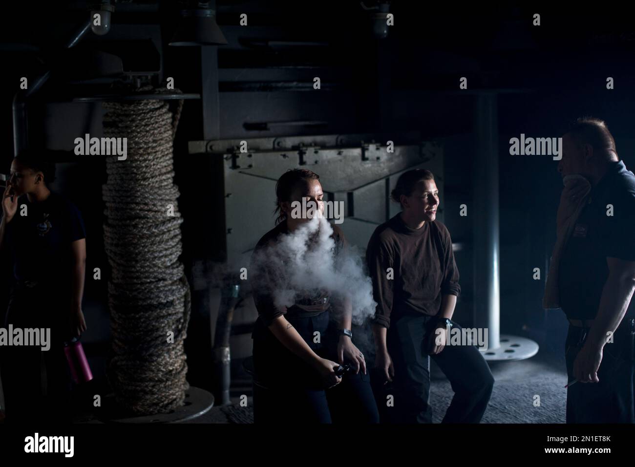 A U.S. Navy sailor puffs e-cigarette smoke out of her nose as she takes ...