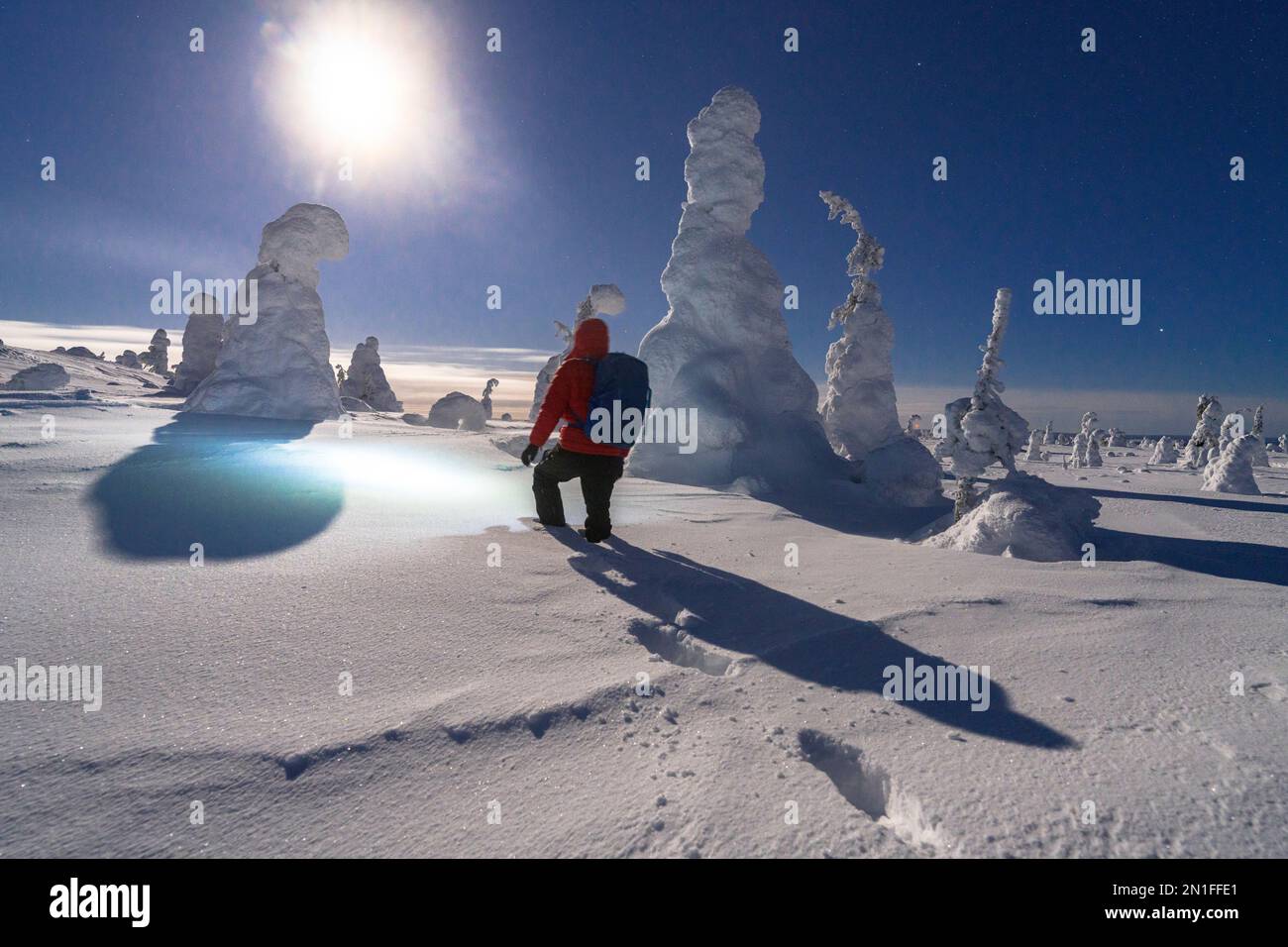Tourist admiring the ice sculptures lit by moon standing in deep snow ...