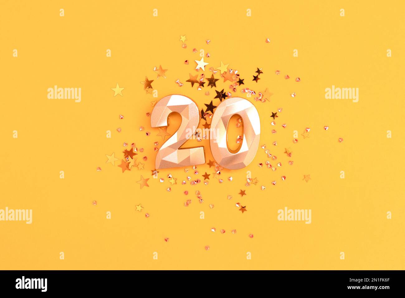 Golden number twenty and stars confetti on a yellow background. Festive ...