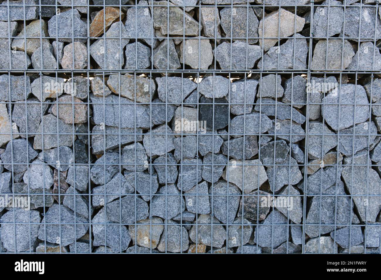 The crushed stone is fixed in the mesh. A fence made of natural stone ...