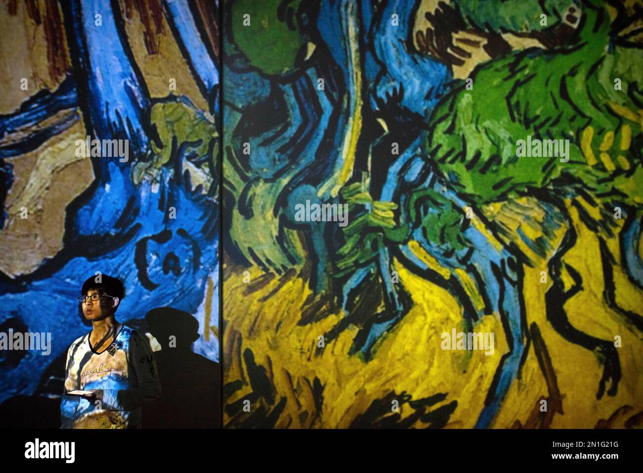A visitor watches as paintings by Vincent van Gogh are projected during ...