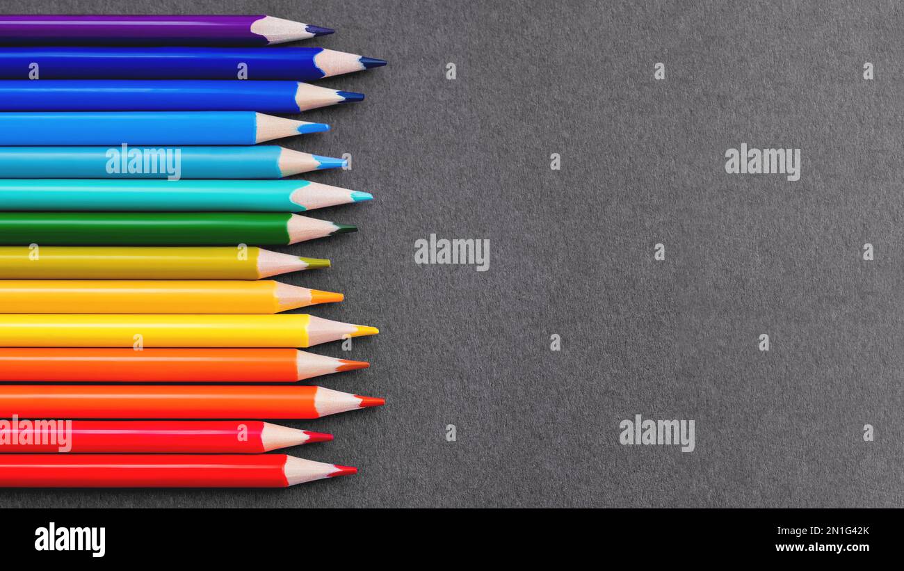 Horizontal row of colorful pencils on grey paper background. School ...
