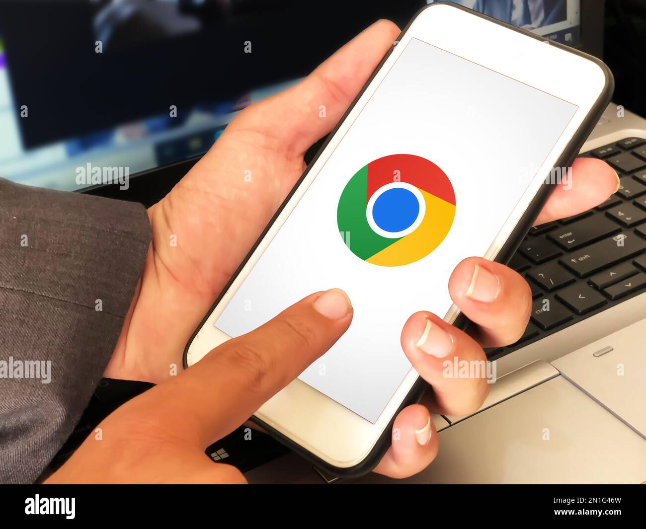 Man using google chrome application on mobile with laptop in the ...