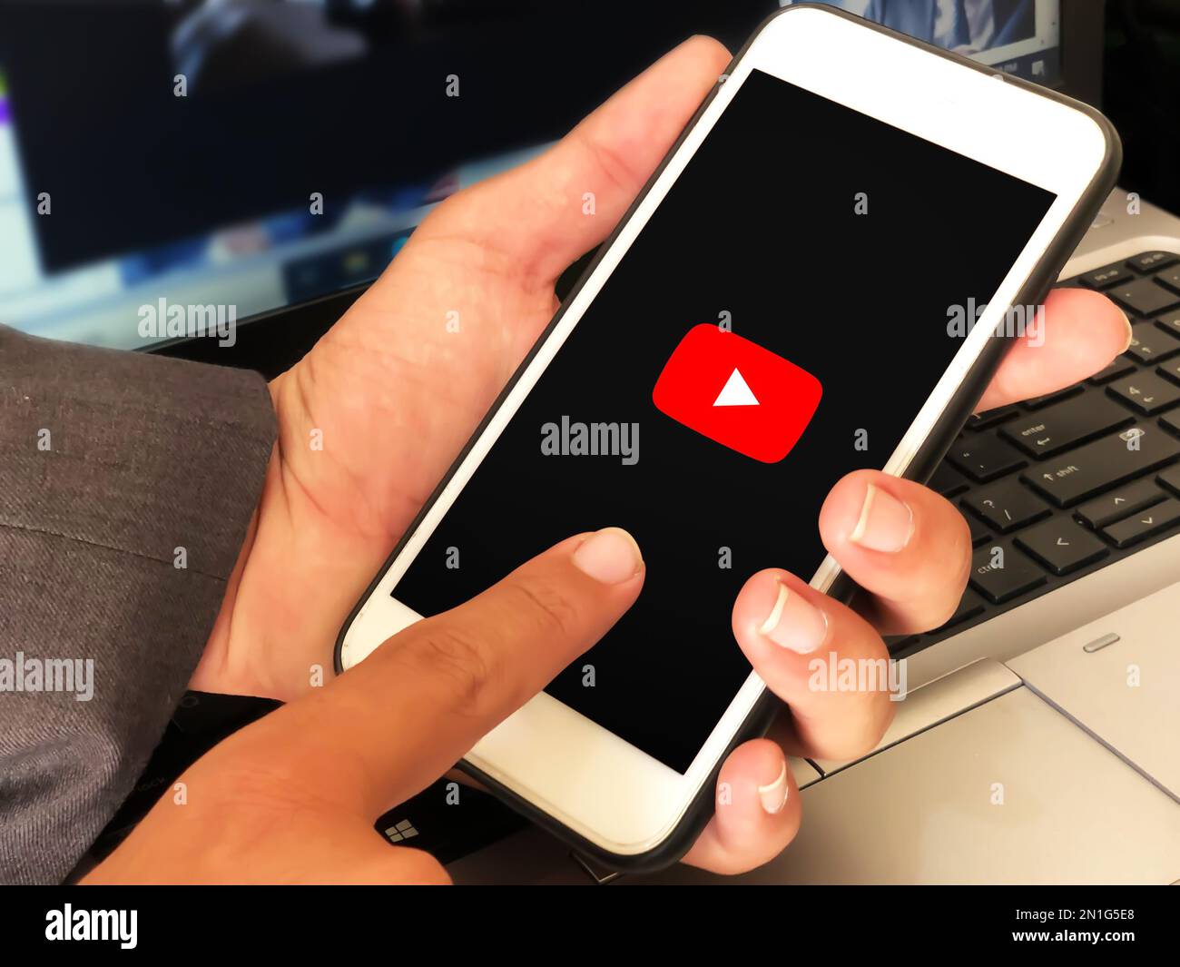 Man using YouTube on mobile with laptop in the background, eidtorial ...