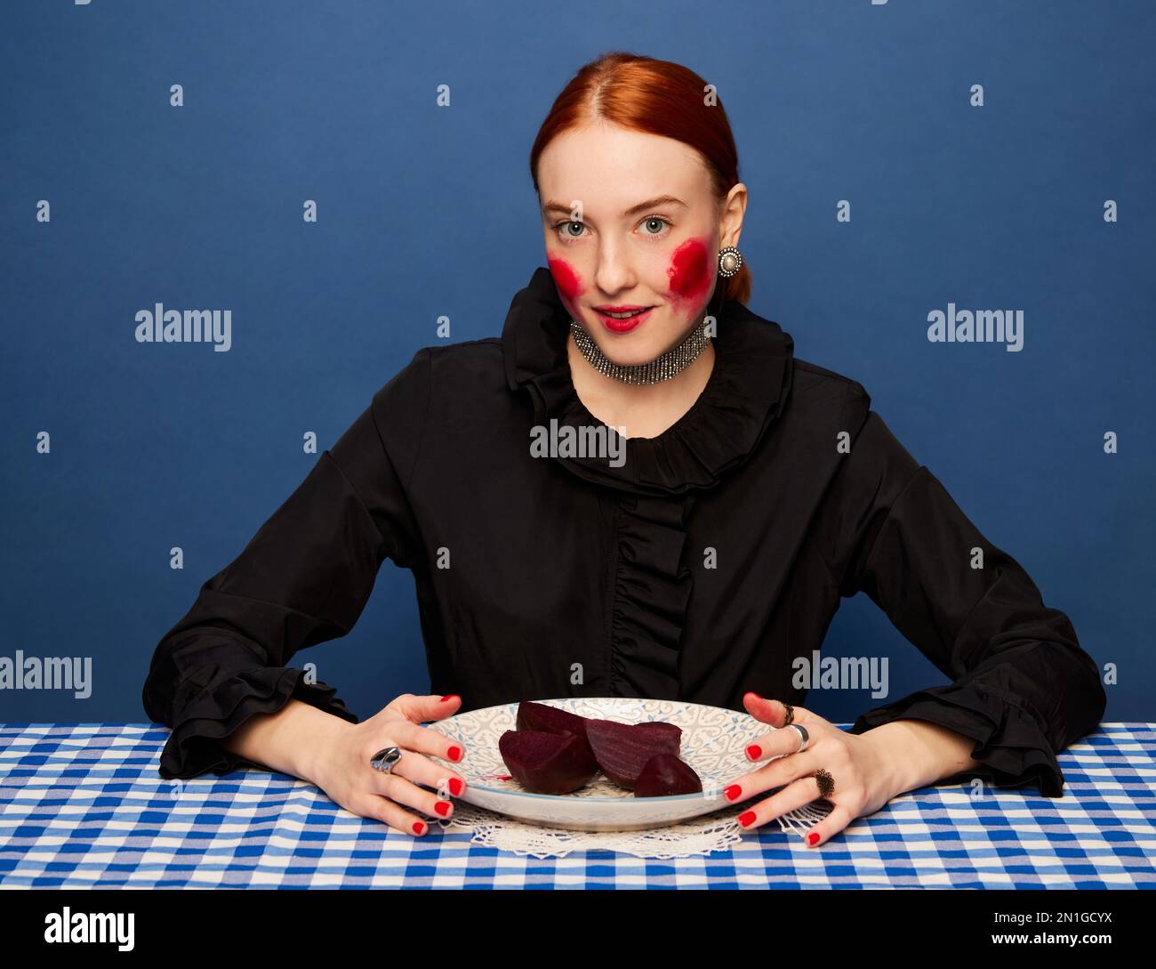 Beetroot cheeks. Young beautiful girl with beet on retro tablecloth ...