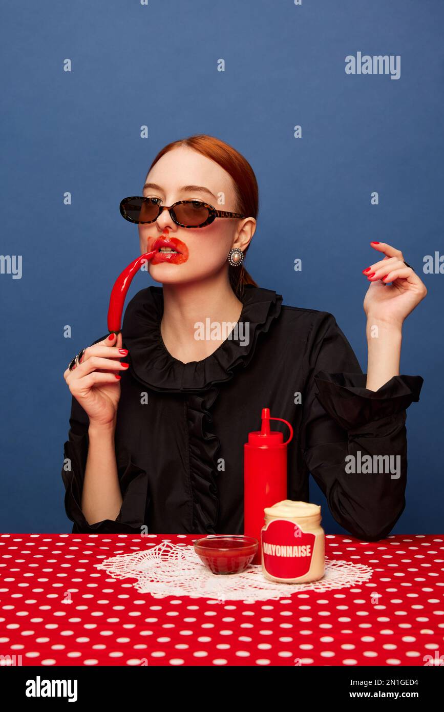 Young beautiful girl eating spicy red chilli pepper and mayonnaise over ...