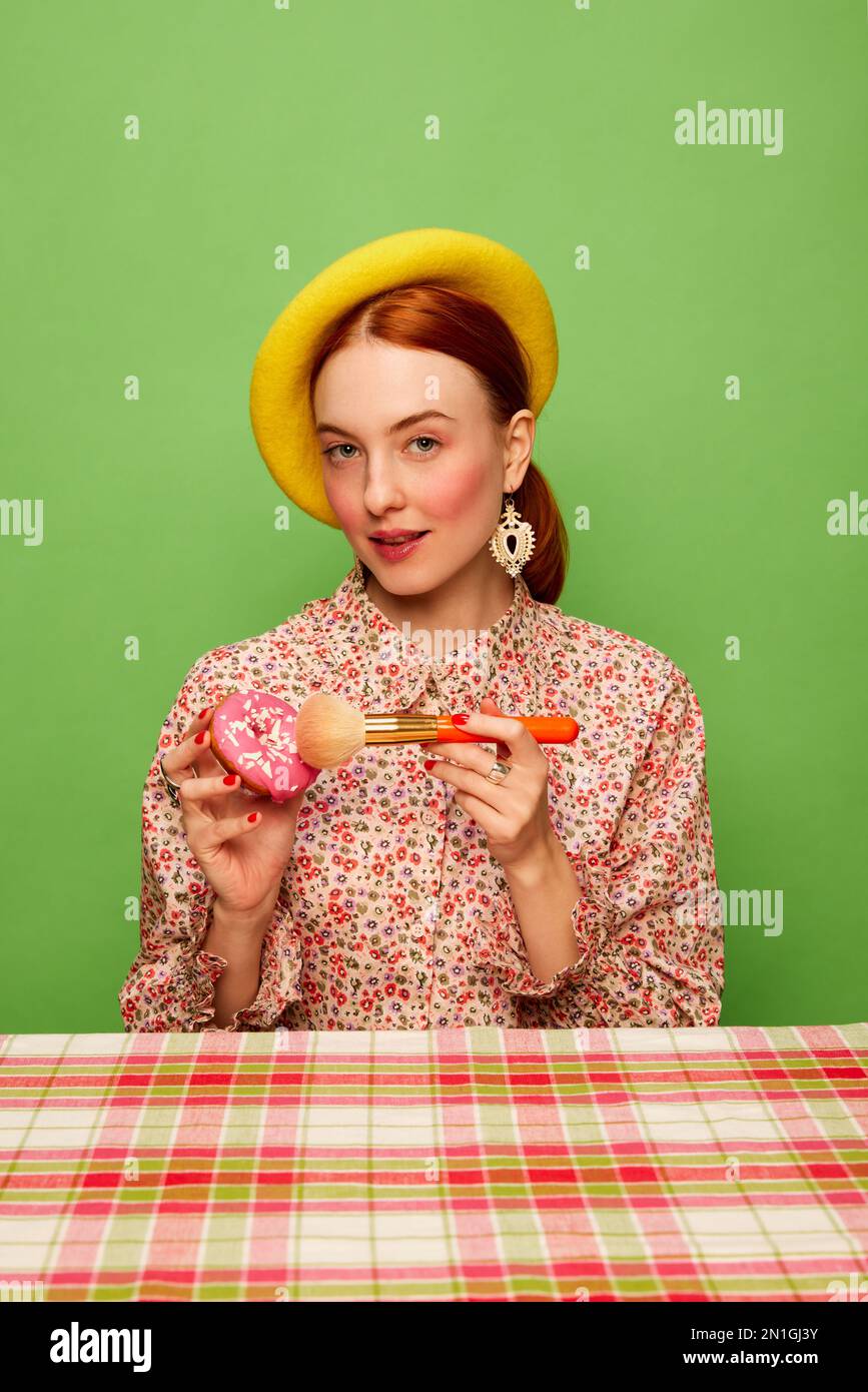 Colorful mood. Beautiful girl with blushing cheeks eating pink donut ...