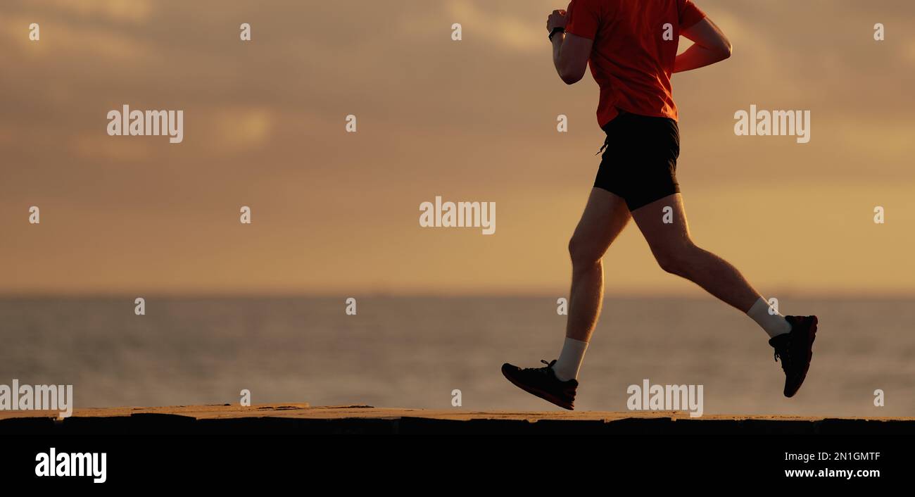 Shot of fit man running along the ocean shore in morning. Healthy male ...