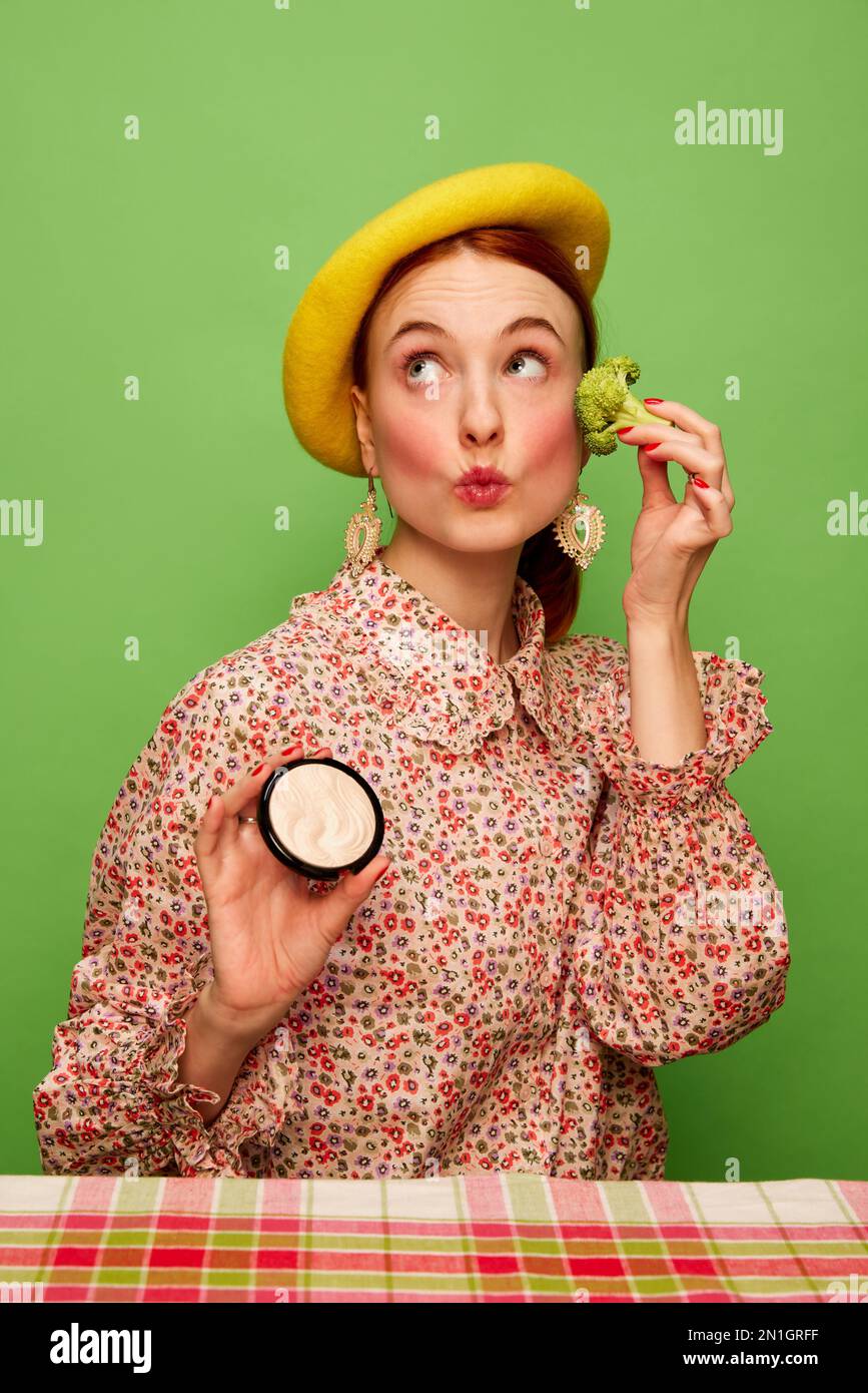 Nutrition. Beautiful young girl in cute applying blush with broccoli ...