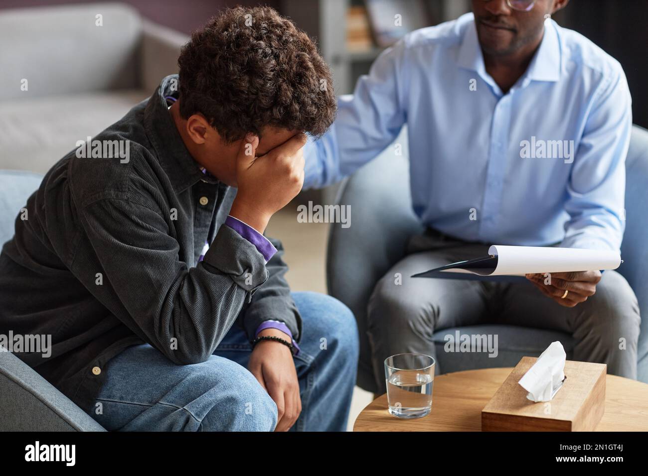 Adolescent psychologist reassuring crying teenage boy Stock Photo - Alamy