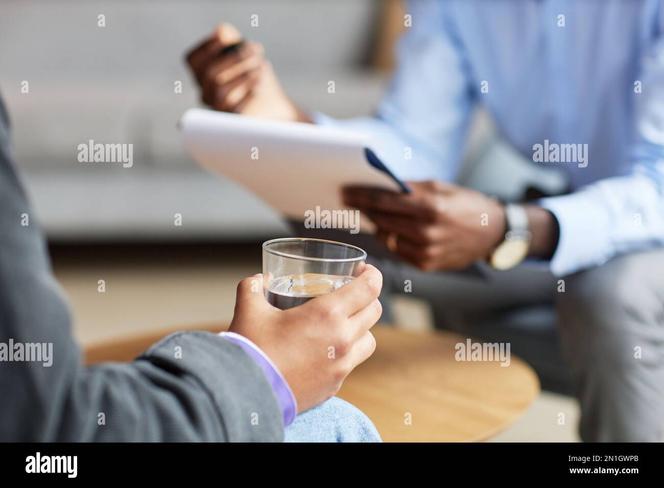 Hand of teenage boy squeezing glass of water when talking to adolescent ...