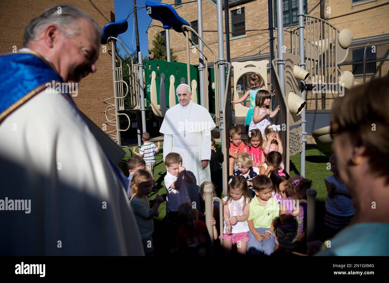Father Dave Fitz-Patrick stands left as children gather in the ...