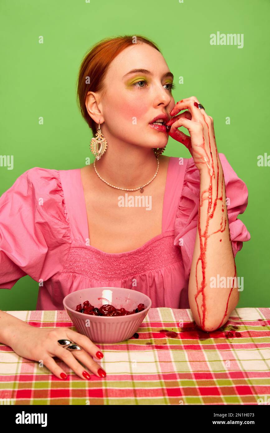 Countryside style. Beautiful young girl in cute pink dress eating berry ...