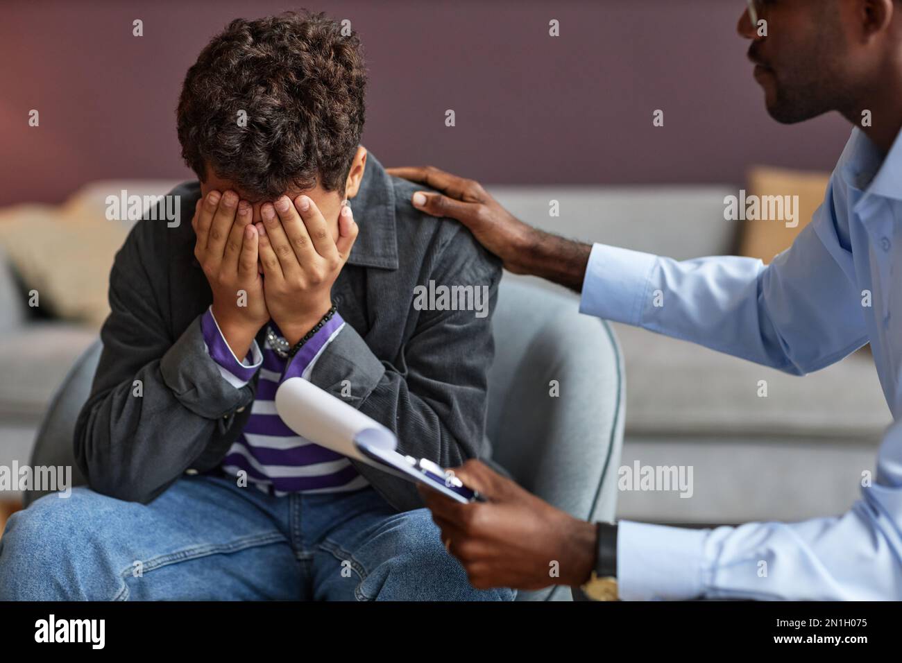 School psychologist reassuring teenage boy crying when talking about ...