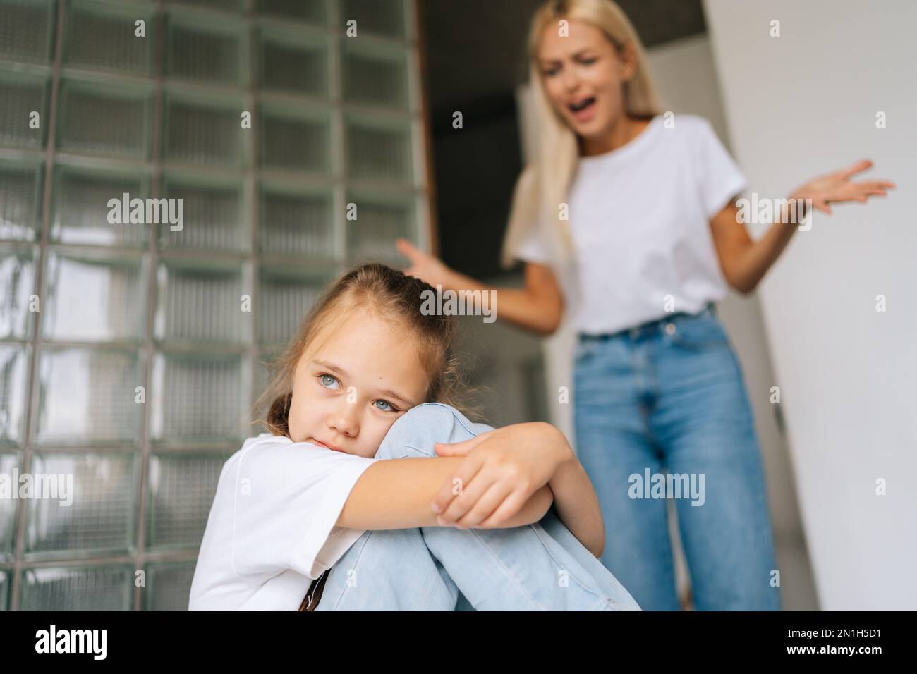 Mad blonde abusive mother emotionally gesturing and shouting at crying ...