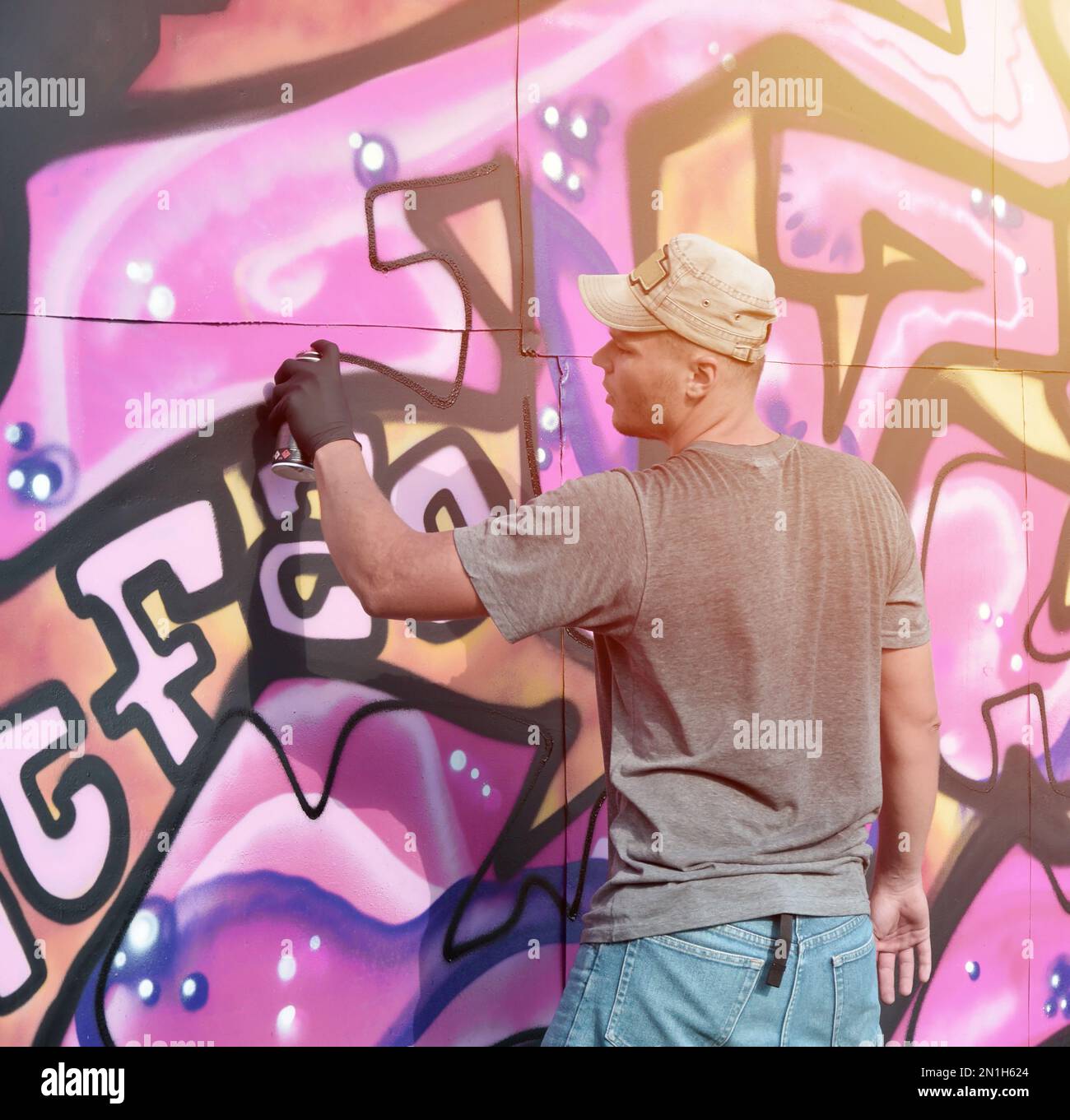 Young caucasian male graffiti artist drawing big street art painting in ...