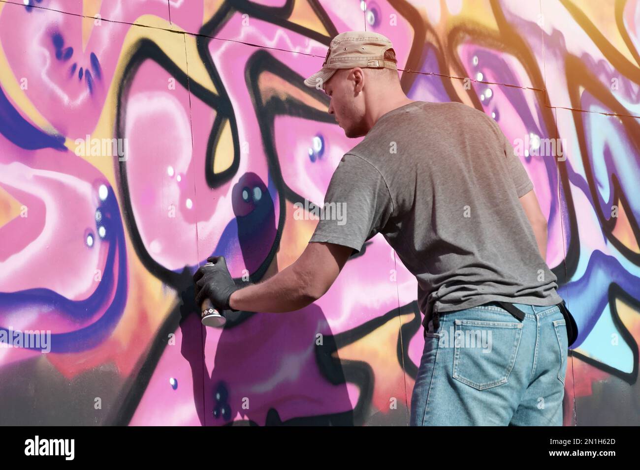 Young caucasian male graffiti artist drawing big street art painting in ...