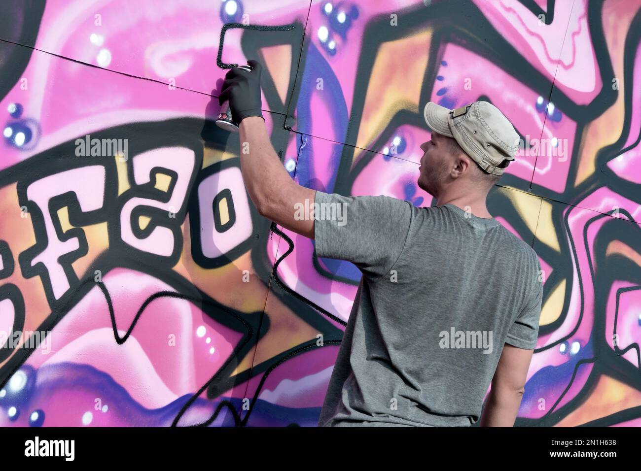 Young caucasian male graffiti artist drawing big street art painting in ...