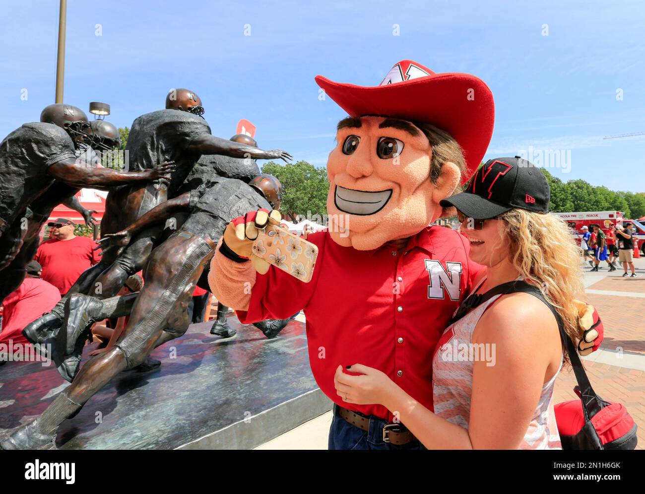 Nebraska mascot Herbie Husker takes a photo with a fan in front of ...