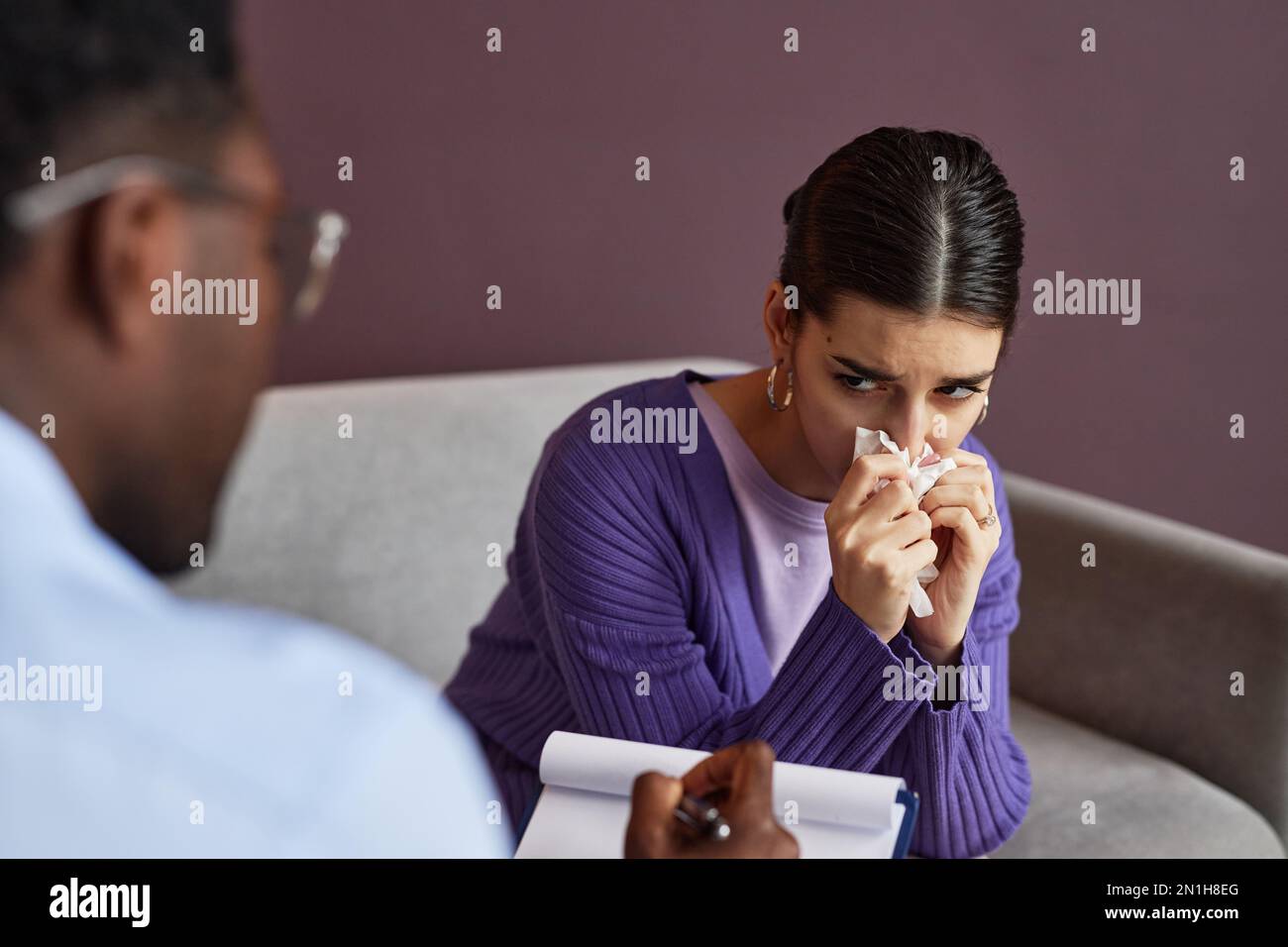 Young woman crying and blowig her nose when talking to therapist Stock ...