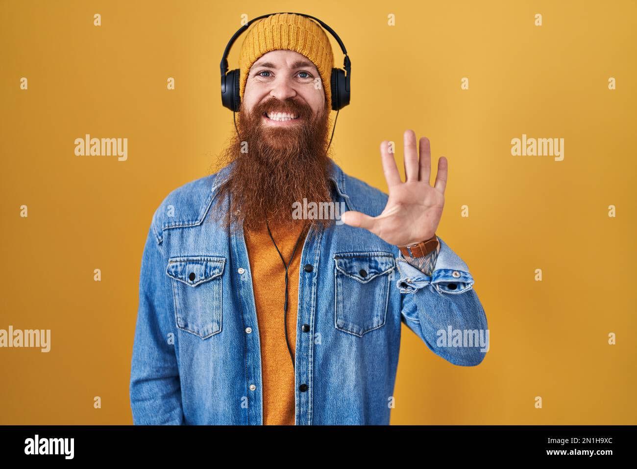 Caucasian man with long beard listening to music using headphones ...