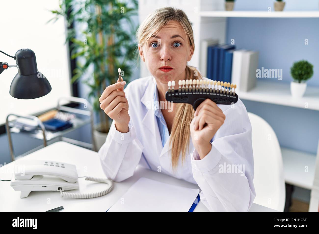 Beautiful dentist woman comparing teeth whitening puffing cheeks with ...