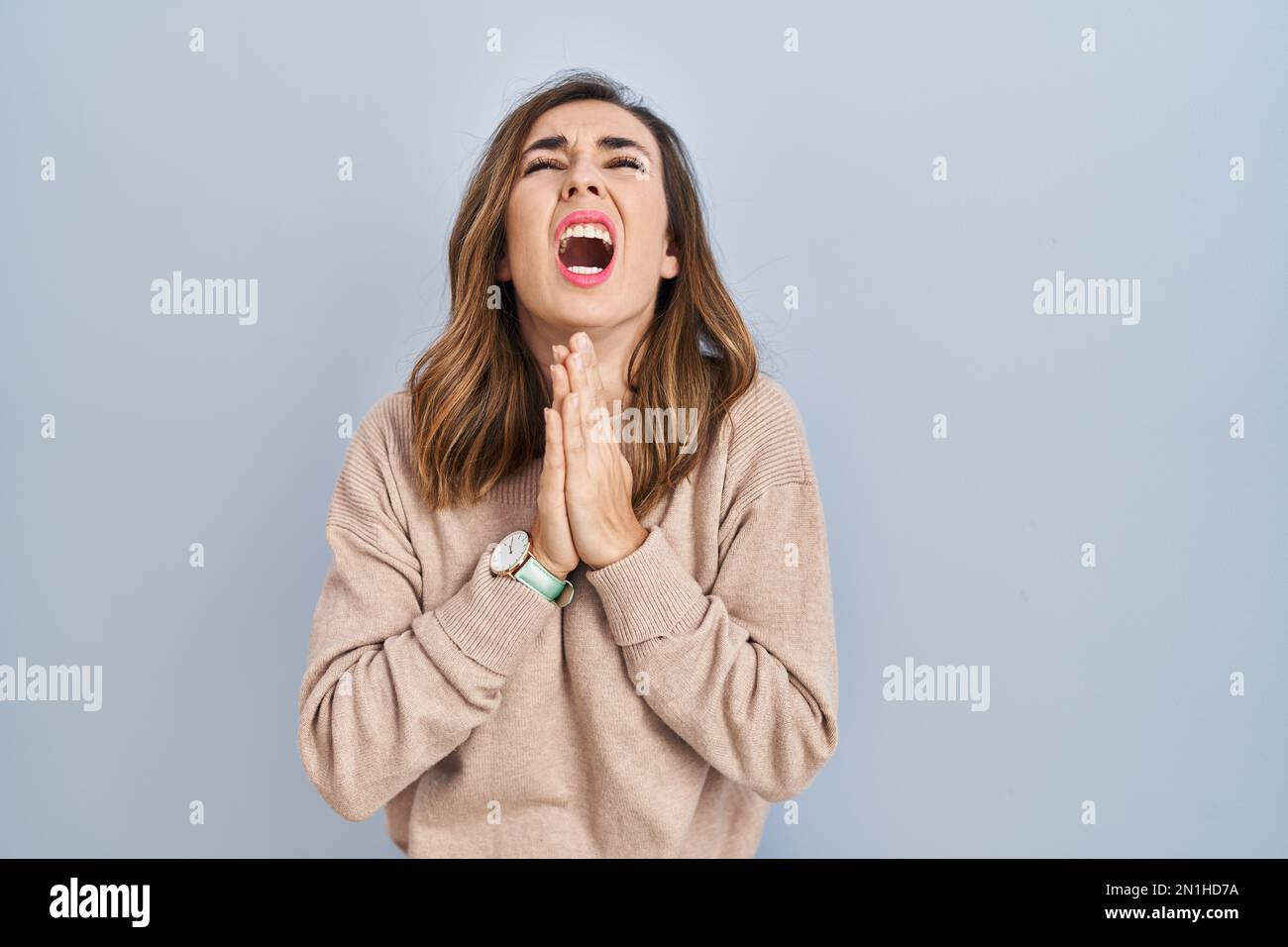 Young woman standing over isolated background begging and praying with ...