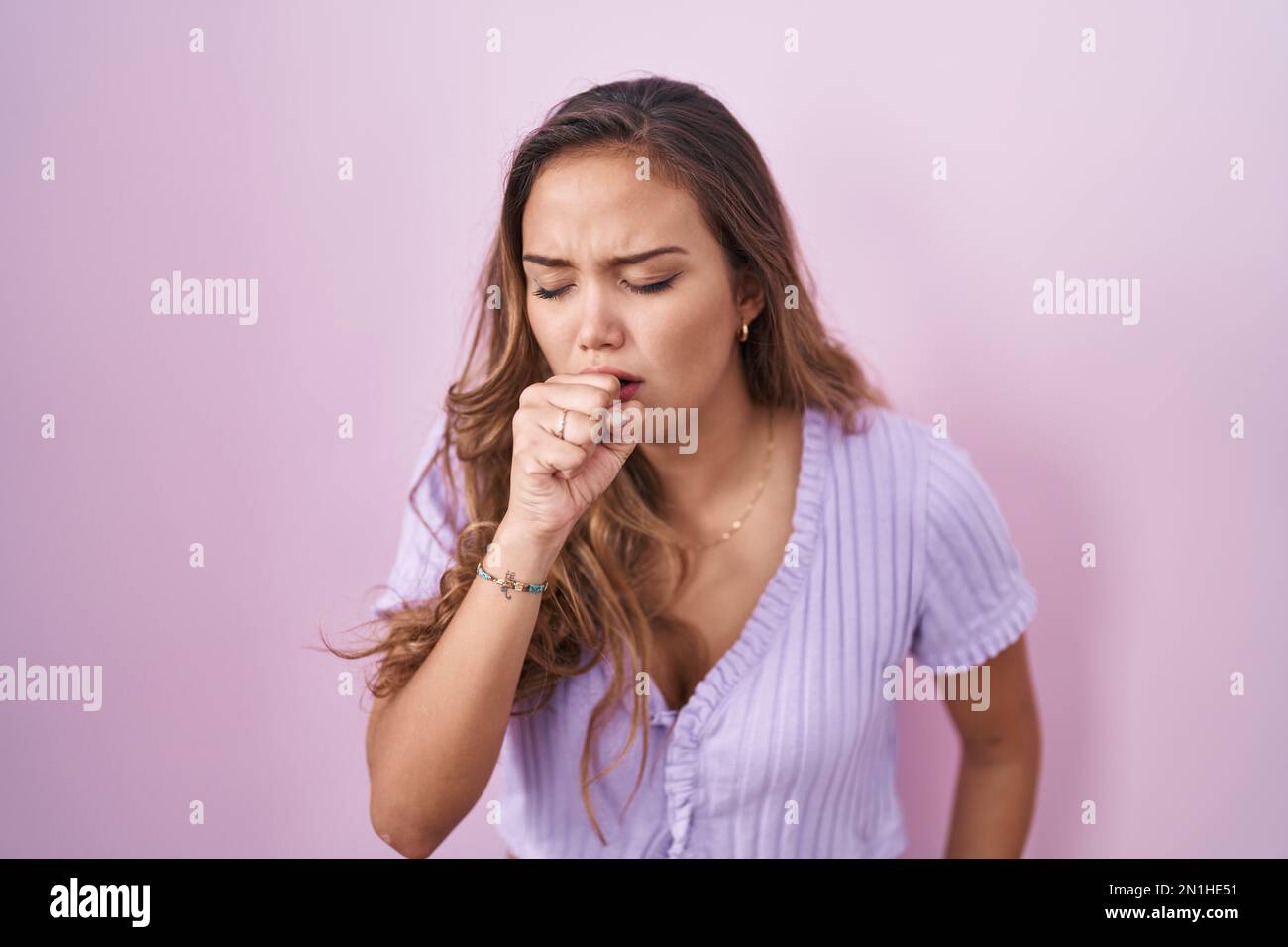 Young hispanic woman standing over pink background feeling unwell and ...