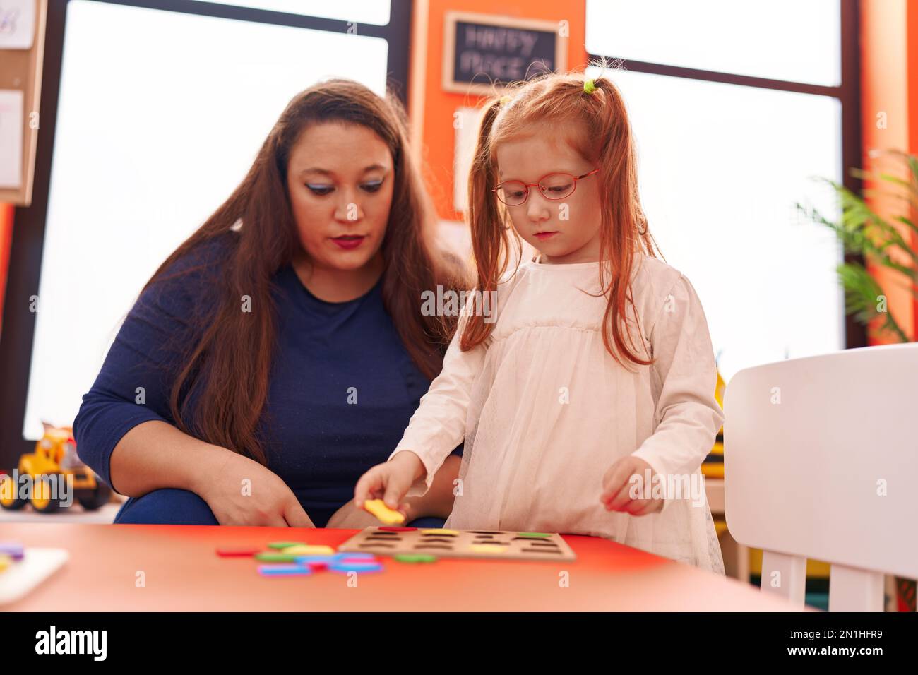 Teacher and student playing with maths puzzle game at kindergarten ...