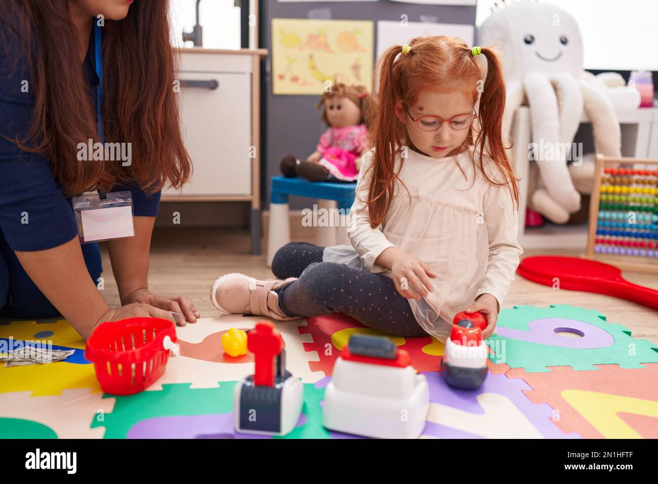 Teacher and student playing supermarket game sitting on floor at ...