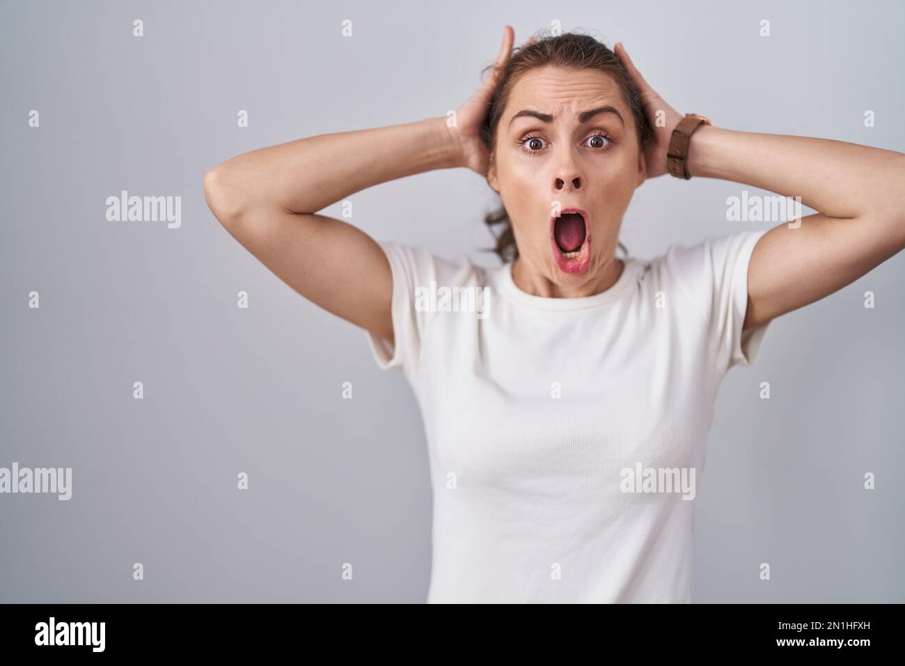 Beautiful brunette woman standing over isolated background crazy and ...