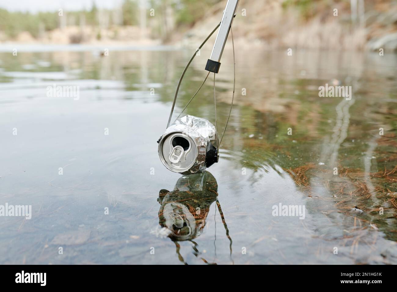 Volunteer using special tool when cleaning lake and picking garbage ...