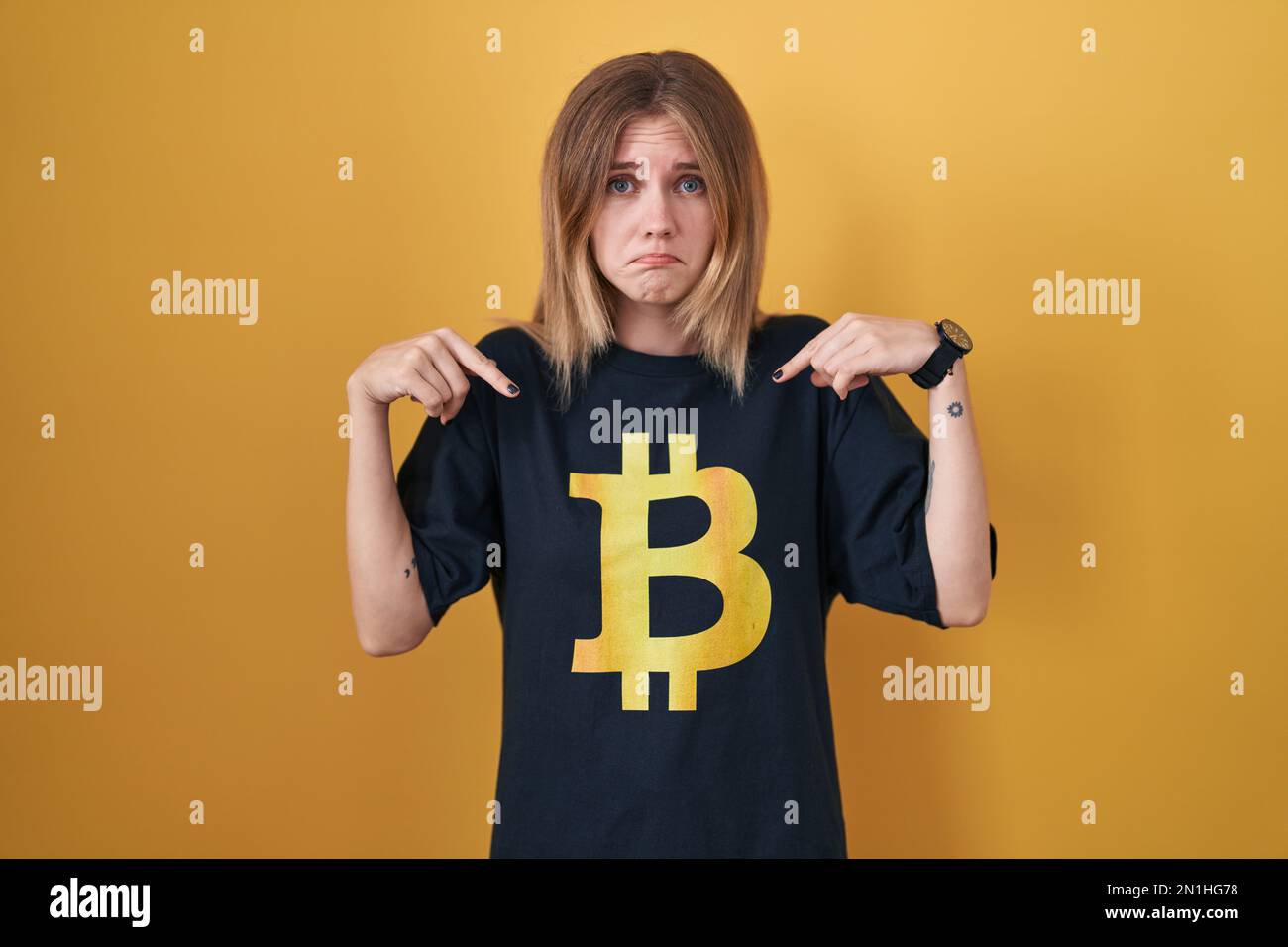 Blonde caucasian woman wearing bitcoin t shirt pointing down looking ...