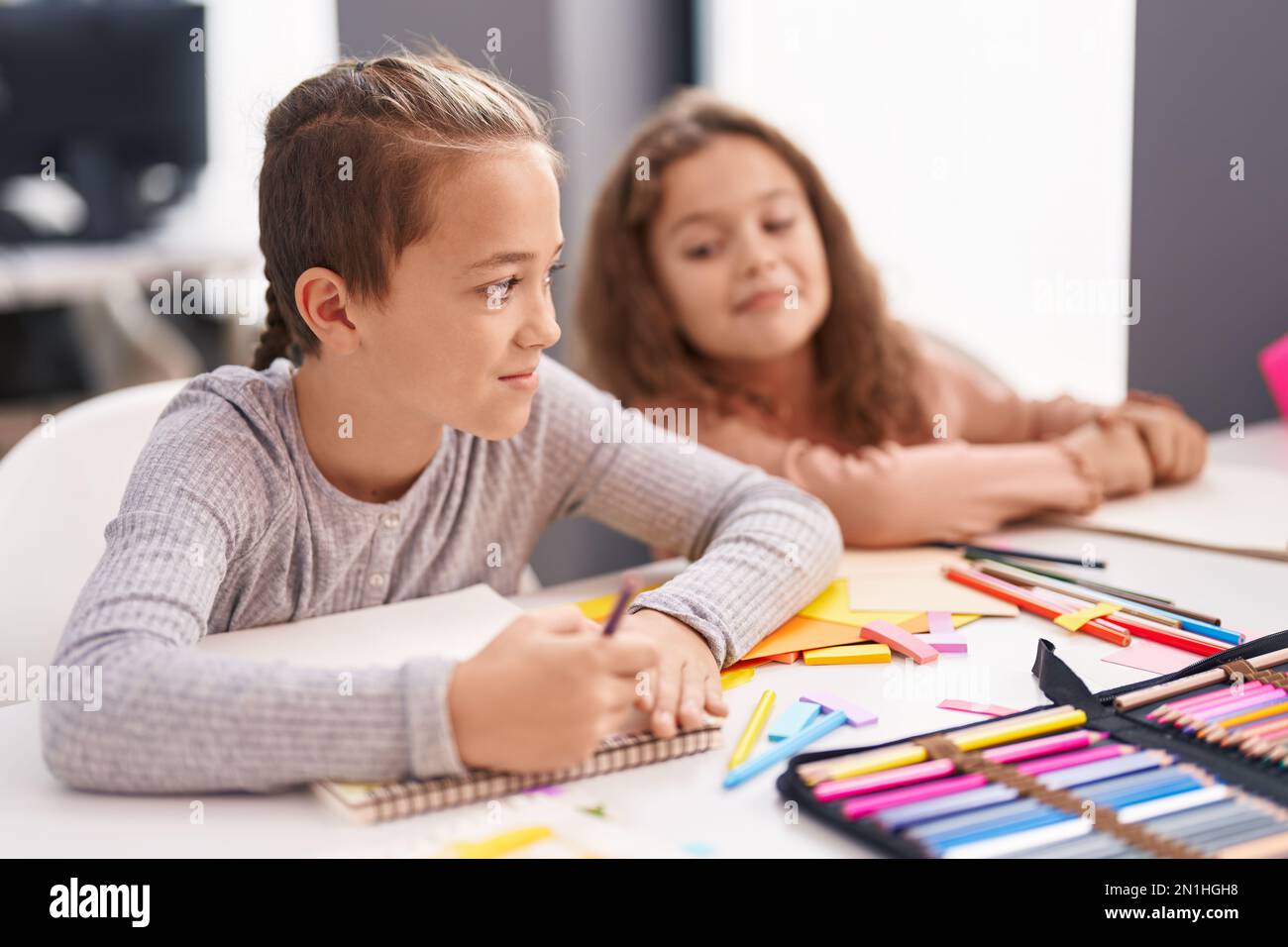 Two kids students sitting on table drawing on notebook paper at ...