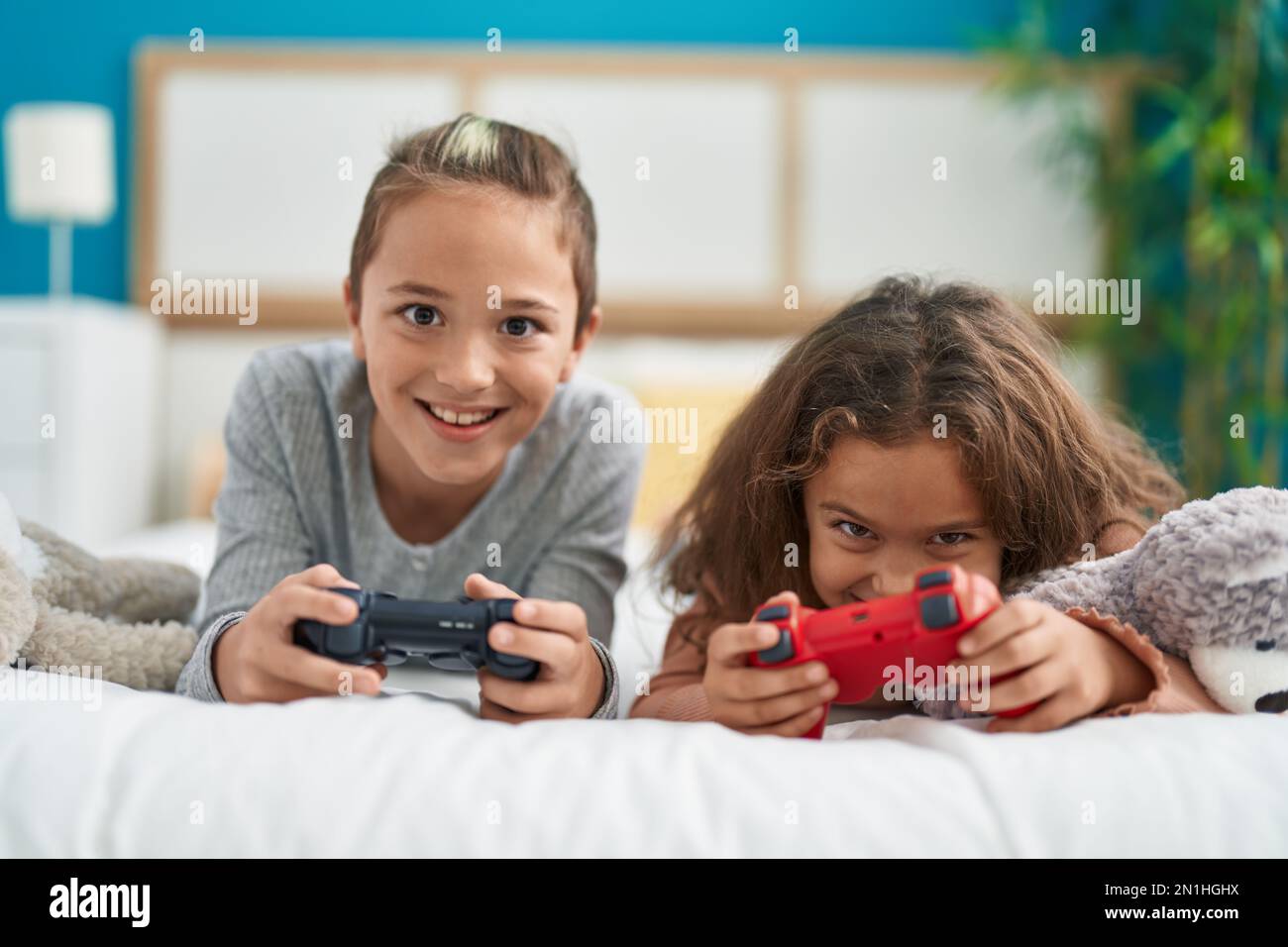 Two kids playing video game lying on bed at bedroom Stock Photo - Alamy
