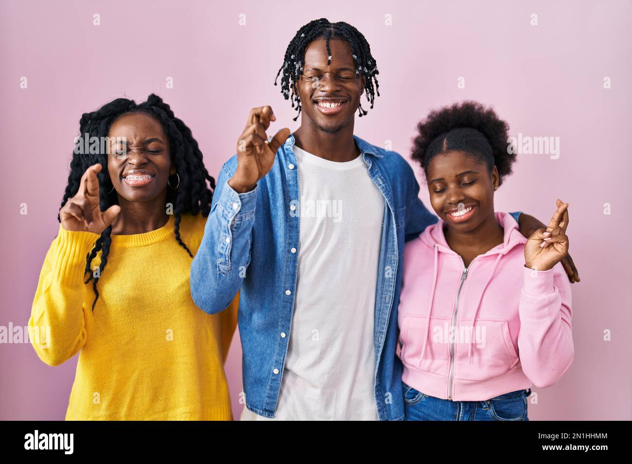 Group of three young black people standing together over pink ...