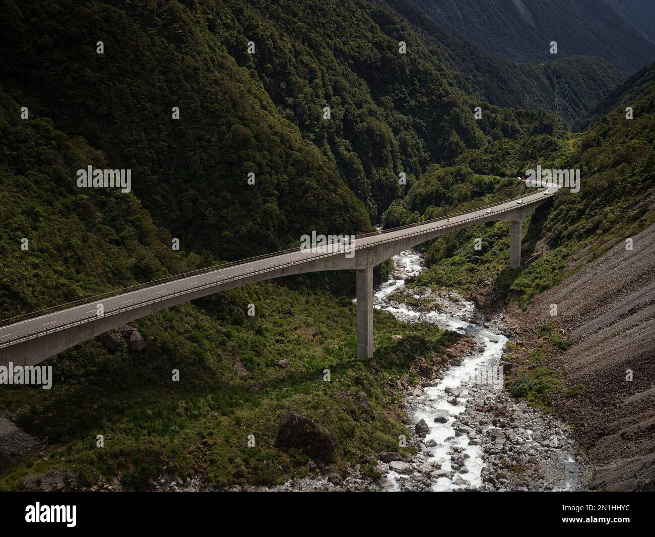 Cars driving on Otira Viaduct concrete bridge over green alpine valley ...