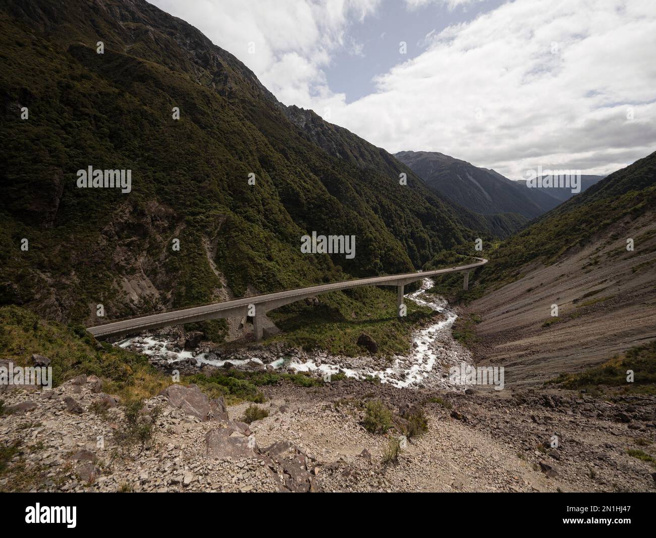 Cars driving on Otira Viaduct concrete bridge over green alpine valley ...