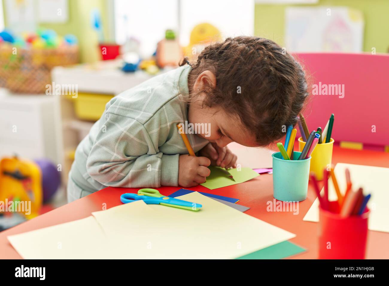 Adorable hispanic toddler student drawing on paper standing at ...