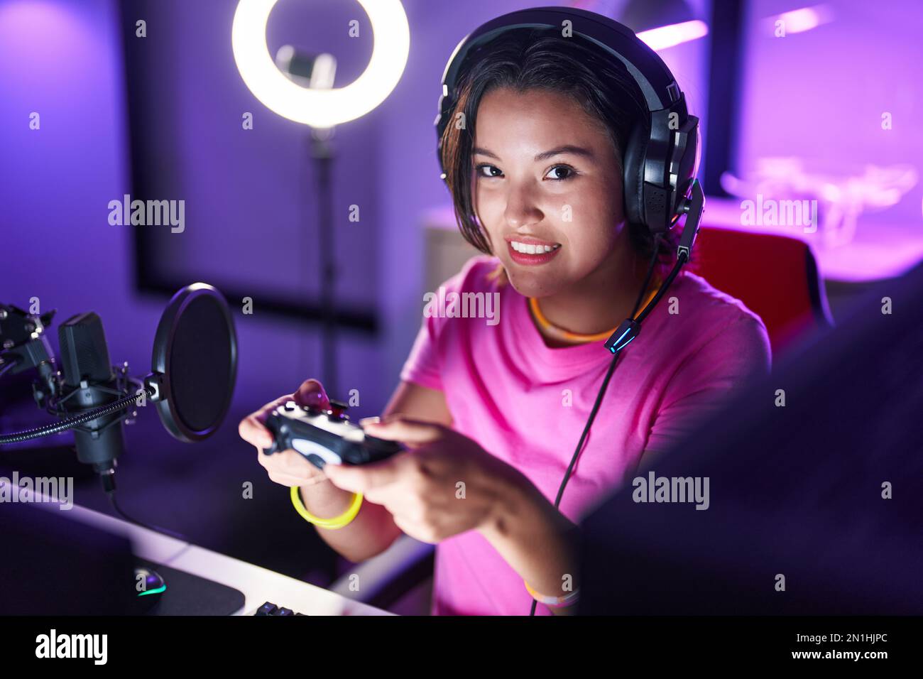 Young hispanic woman streamer playing video game using joystick at ...