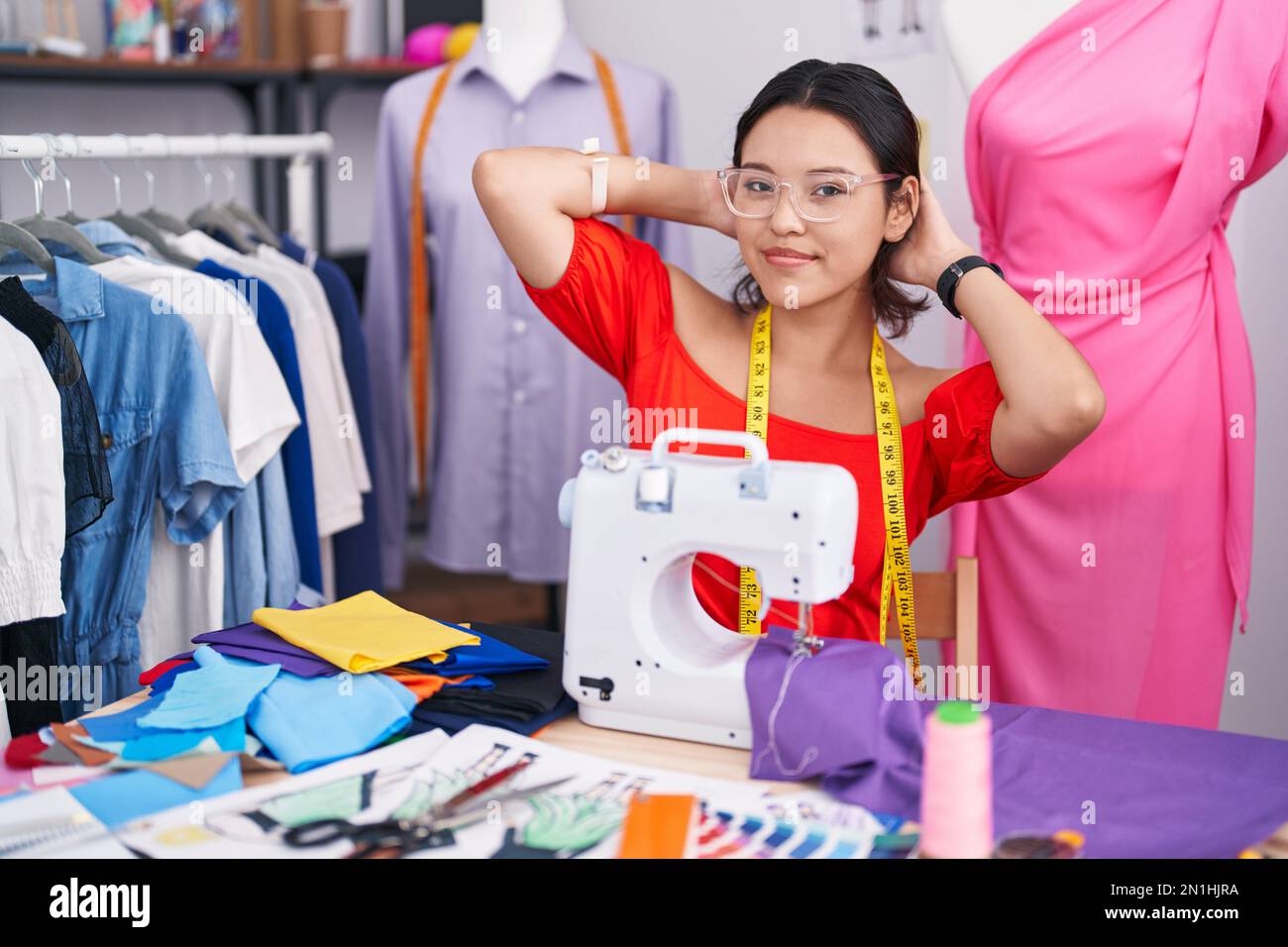 Hispanic young woman dressmaker designer using sewing machine relaxing ...