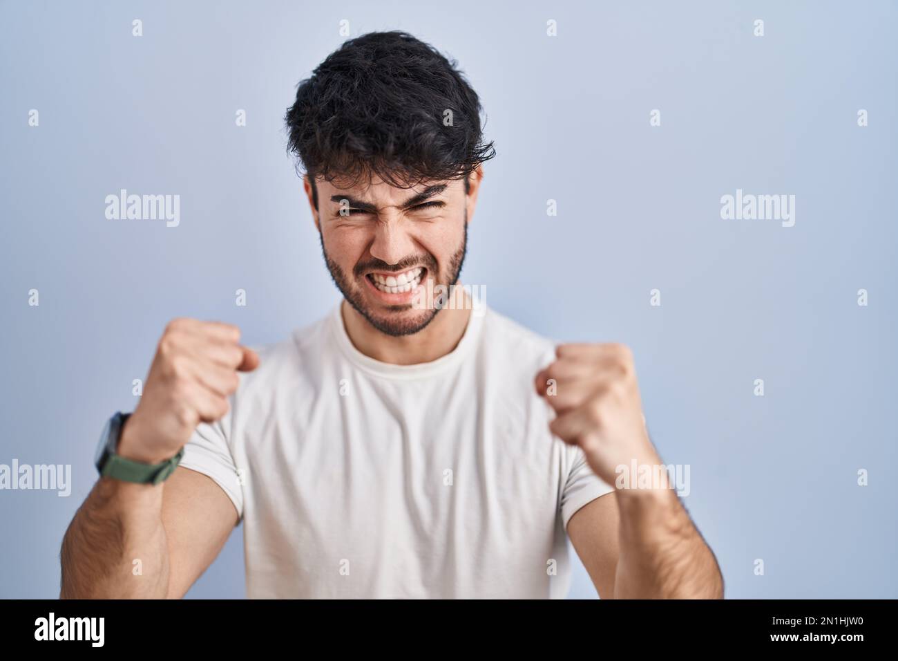 Hispanic man with beard standing over white background angry and mad ...