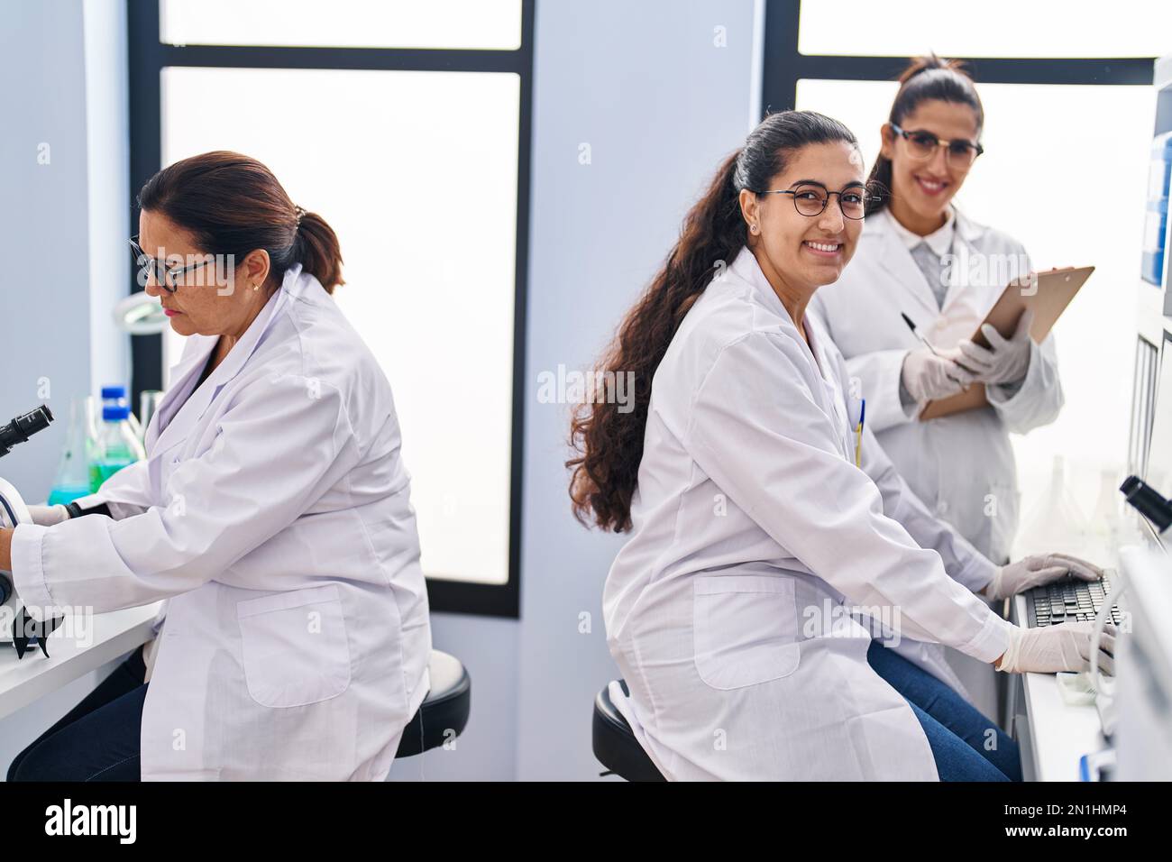 Three woman scientists holding sample write on checklist at laboratory ...