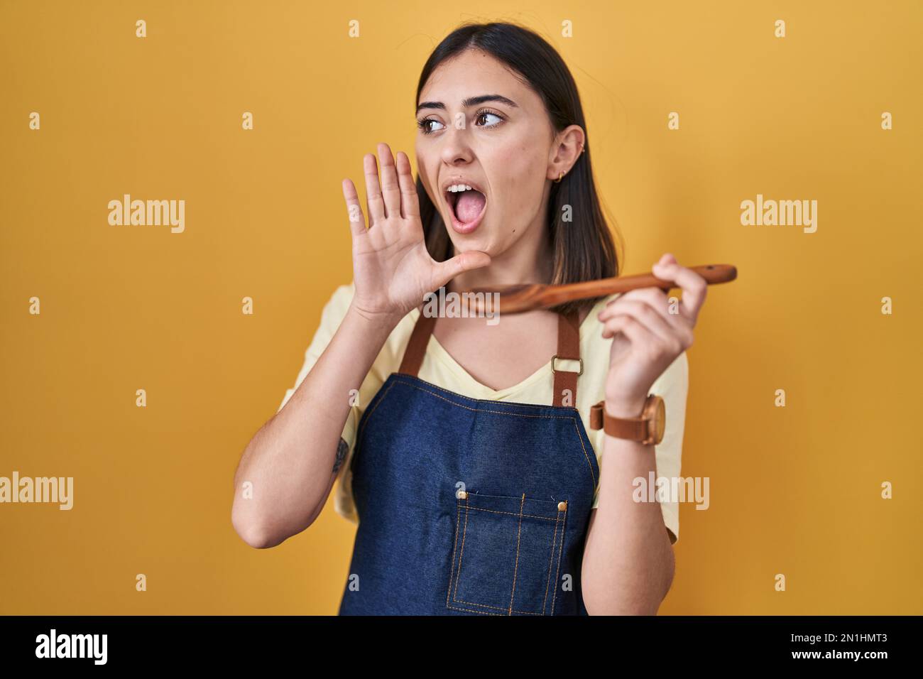 Hispanic girl eating healthy wooden spoon shouting and screaming loud ...