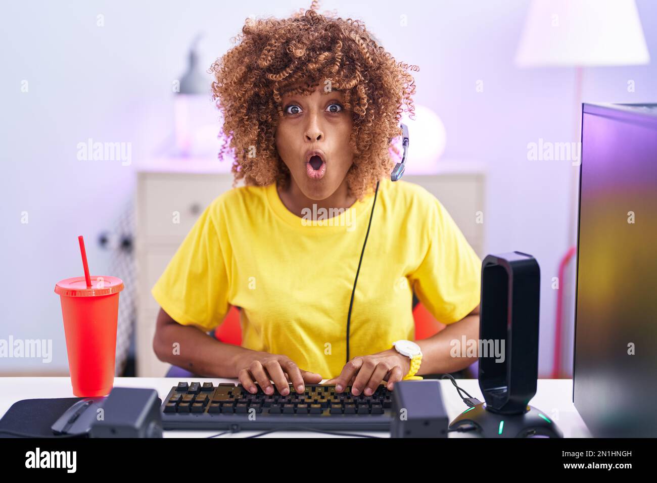 Young hispanic woman with curly hair playing video games wearing ...